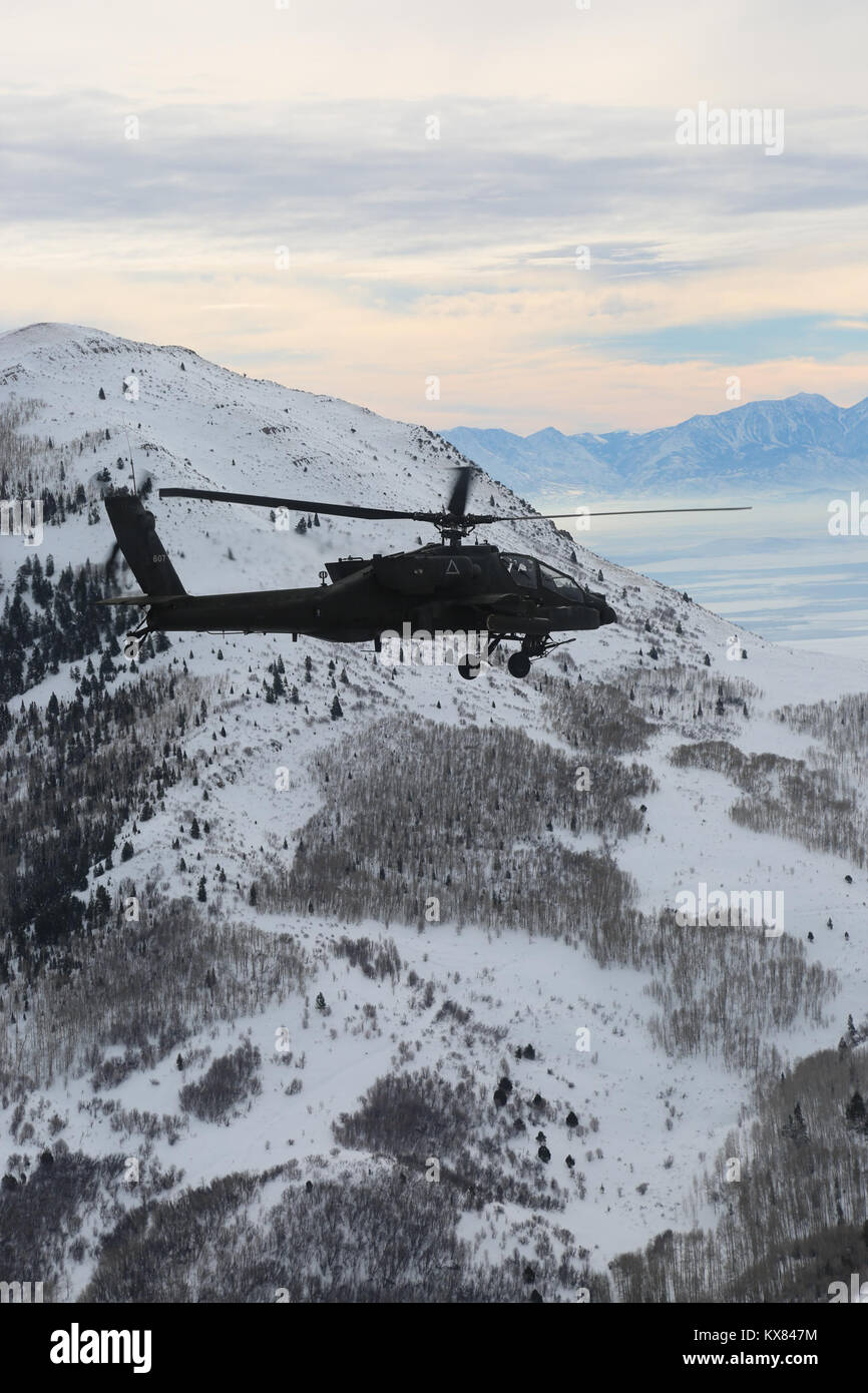 US Army National Guard flying AH-64 Apache military helicopter in snowy winter mountains Stock ...