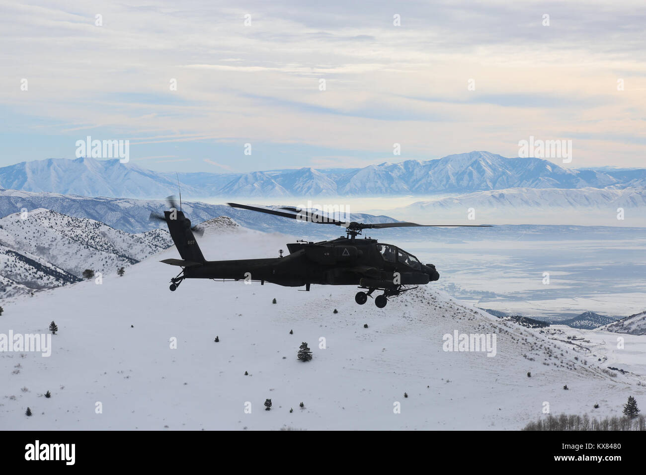 US Army National Guard flying AH-64 Apache military helicopter in snowy winter mountains Stock ...