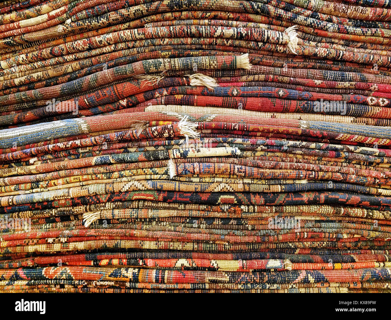 Stack of colorful handmade antique Oriental style rugs and carpets ...