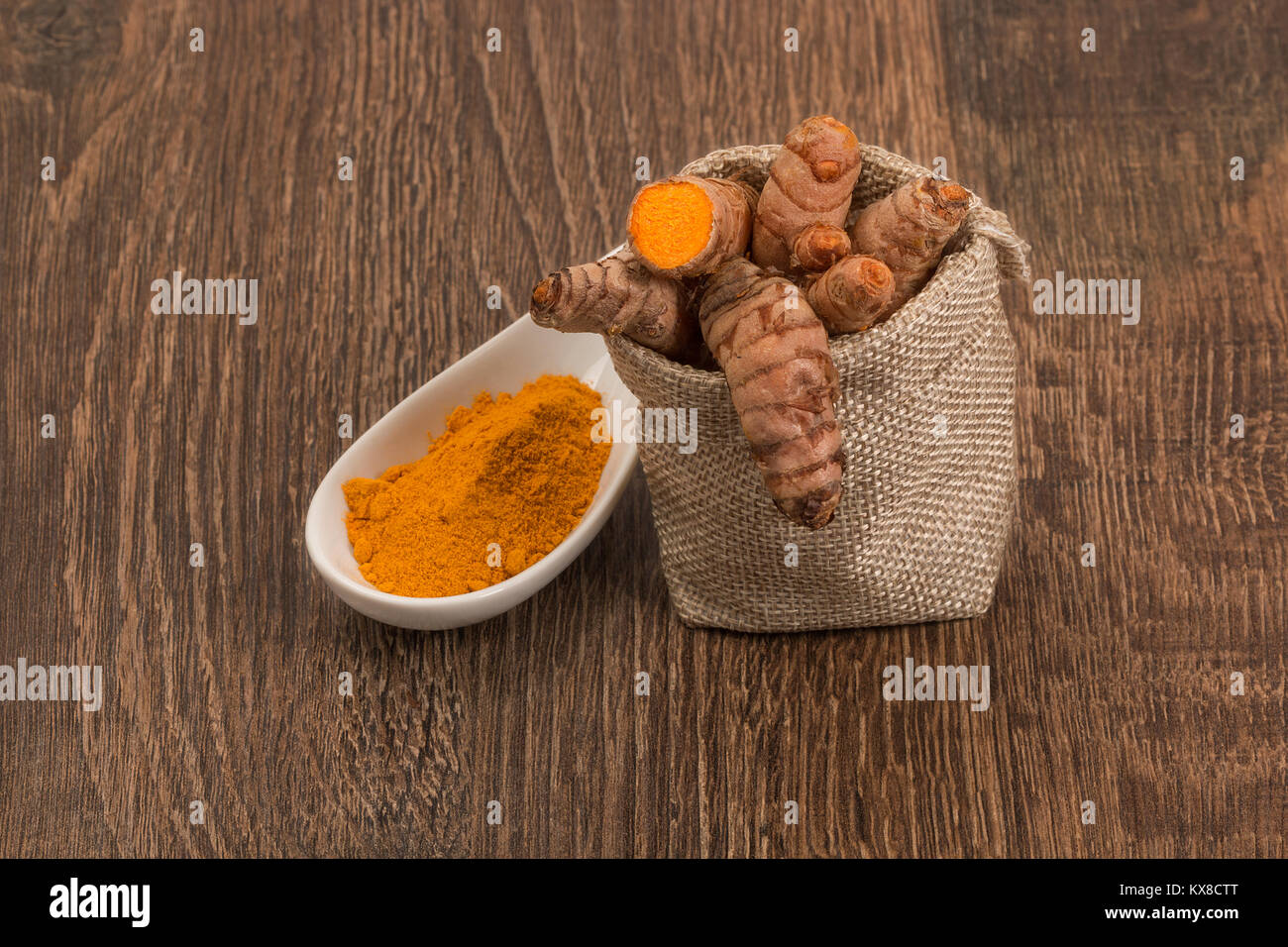 Raw turmeric root in burlap sack on wooden surface Stock Photo - Alamy