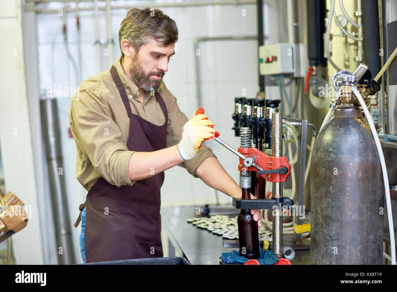 Bearded Worker Using Bottle Capper Stock Photo - Alamy