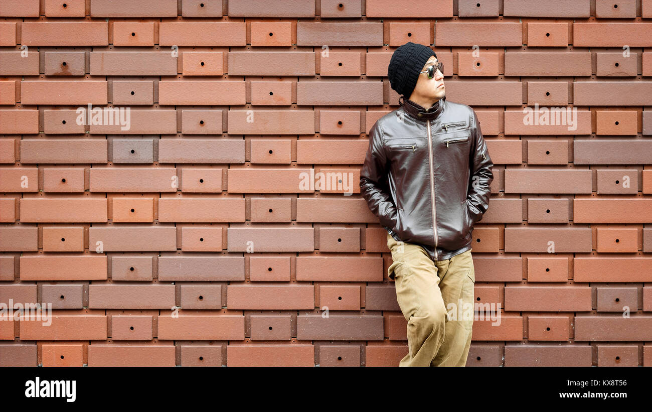 An Asian Man in a Brown Jacket Leans His Back Against the Wall Stock ...