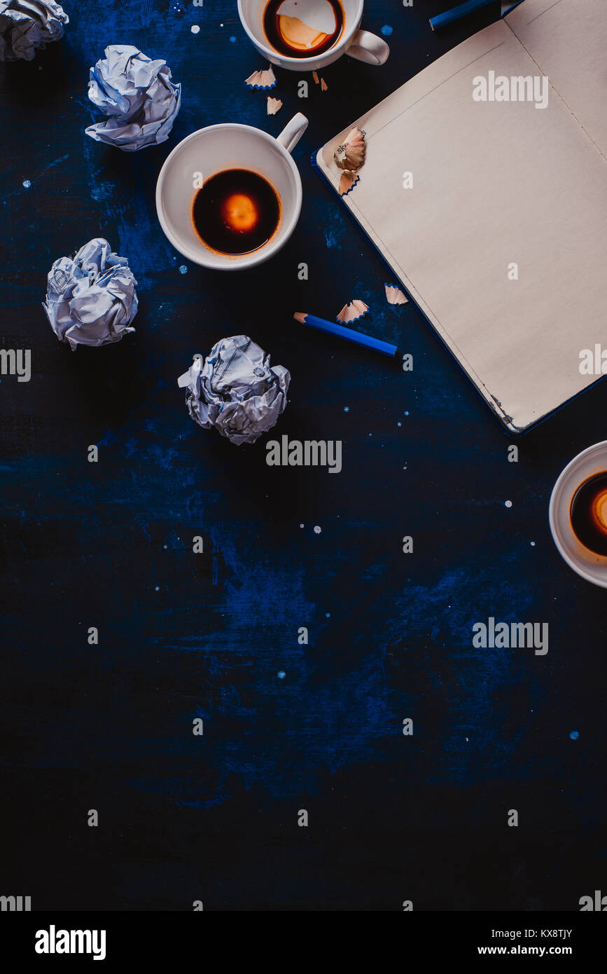 Writers block concept with open notepad, empty coffee cups, pencils and ...