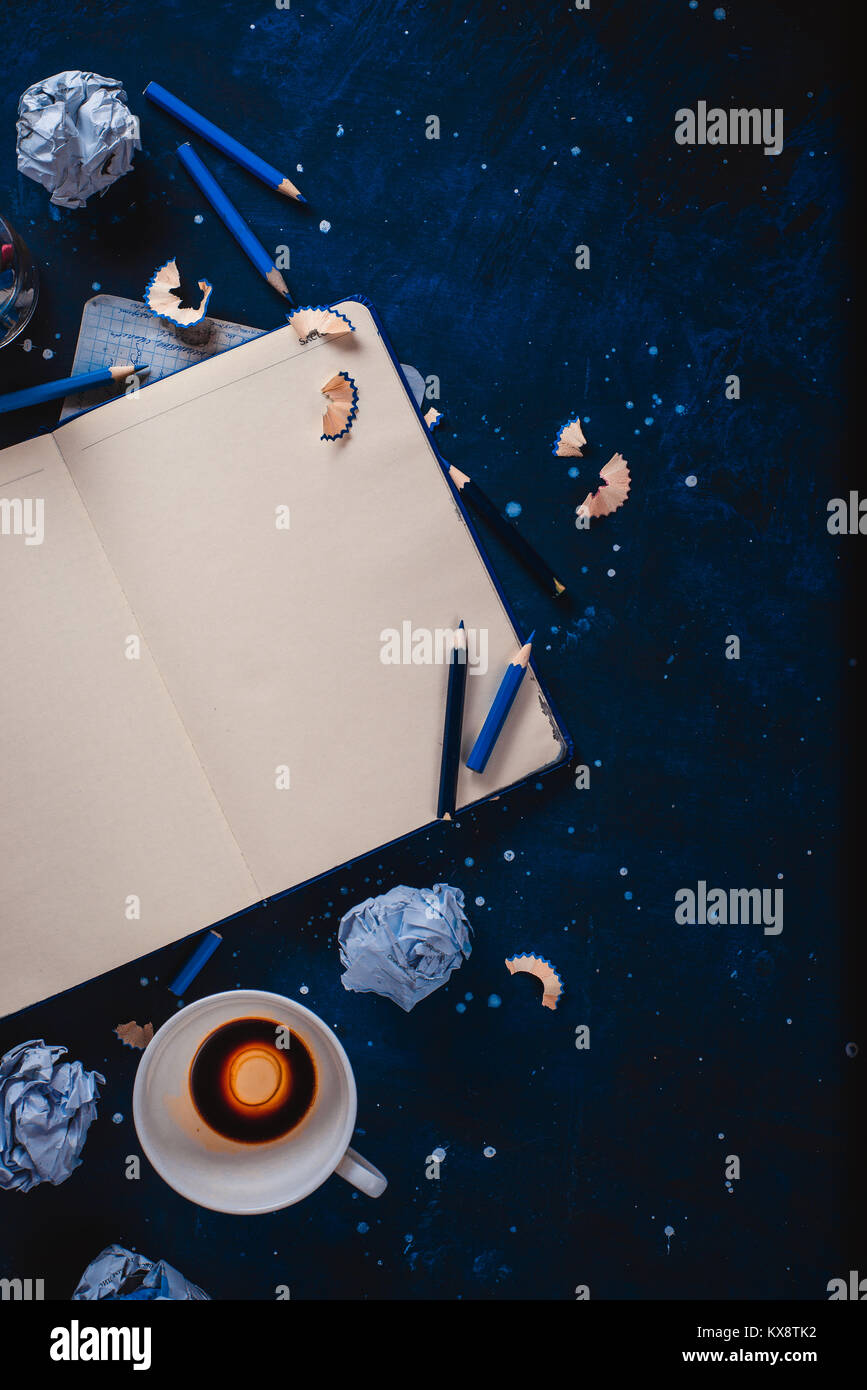 Writers block concept with open notepad, empty coffee cups, pencils and ...