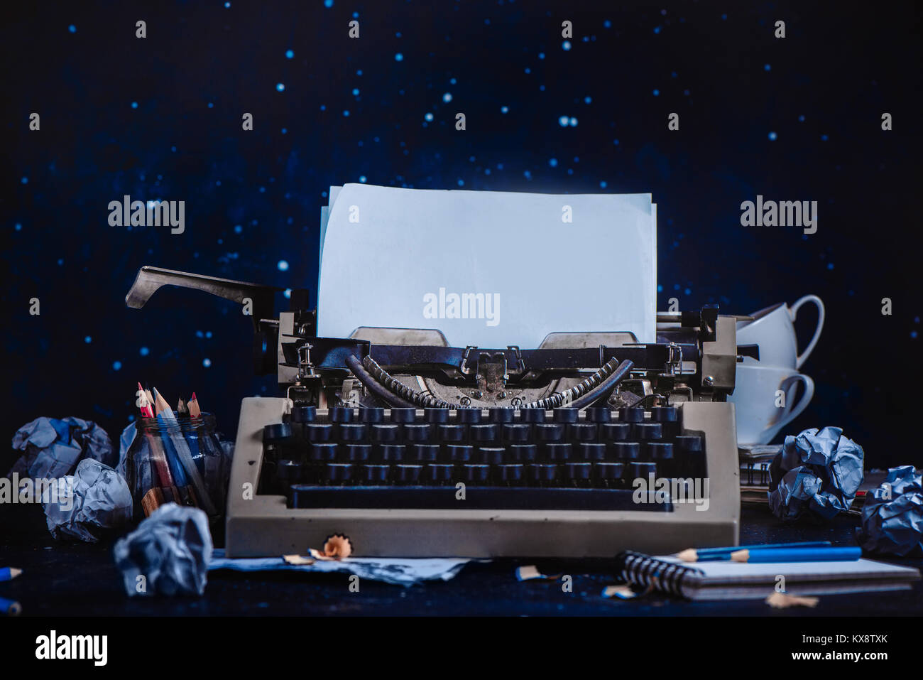 Modern typewriter with sheets of paper, empty coffee cups, pencils and ...