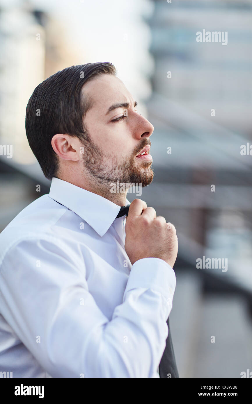 Young businessman with labored breathing from stress looses his tie ...