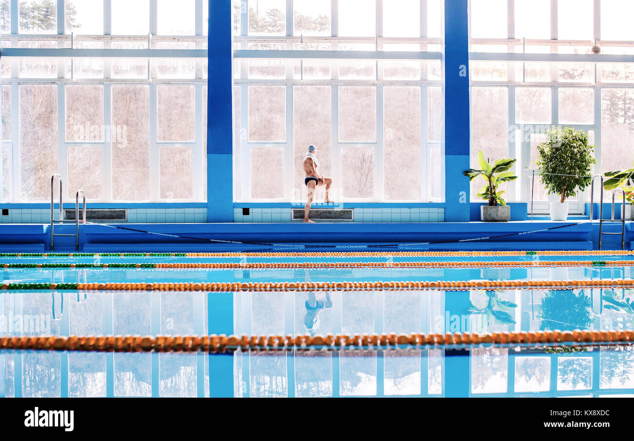 Senior man stretching by the indoor swimming pool Stock Photo - Alamy