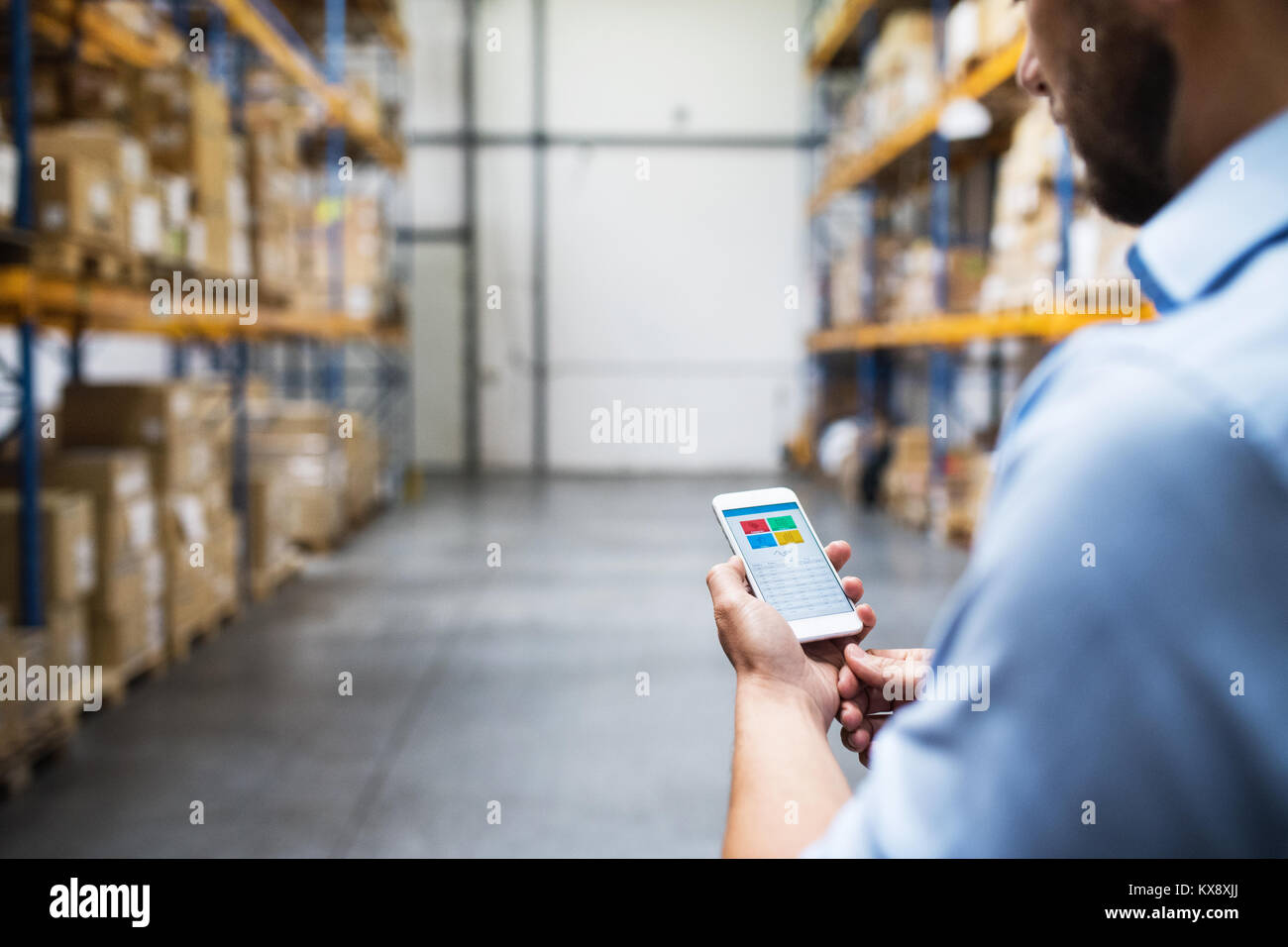Man warehouse worker with a smartphone Stock Photo - Alamy