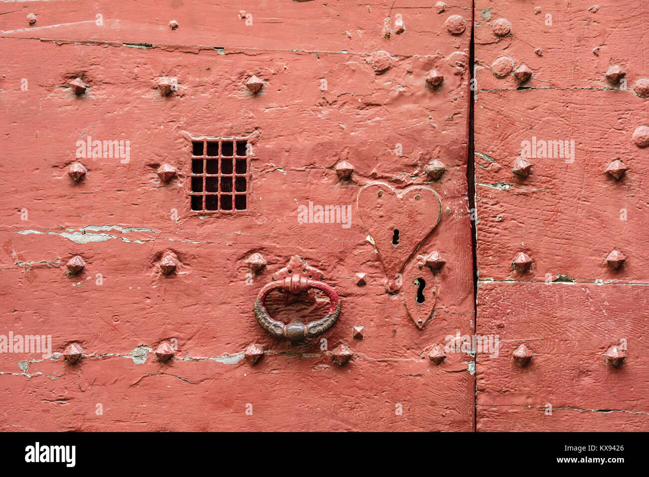 Closeup view of an old red door of medieval style with metallic rivets ...