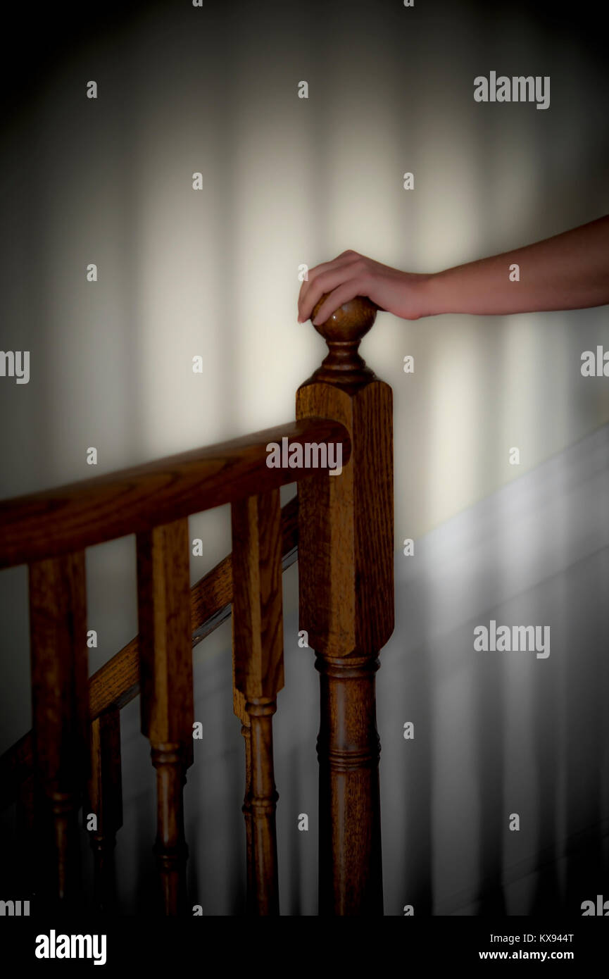 woman's hand on a pillar of stairway railing in a traditional interior ...