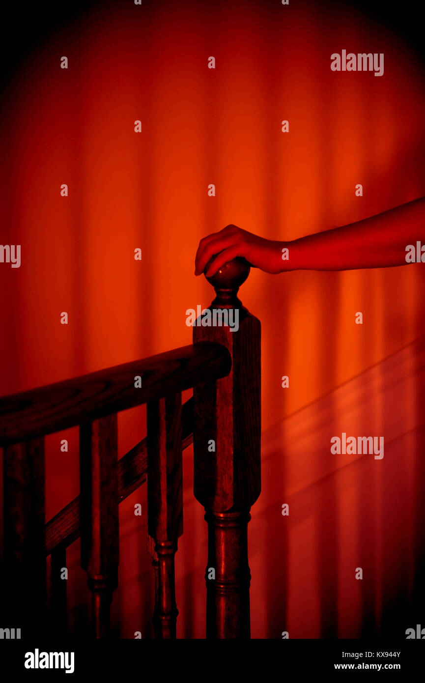woman's hand on a pillar of stairway railing in a traditional interior ...