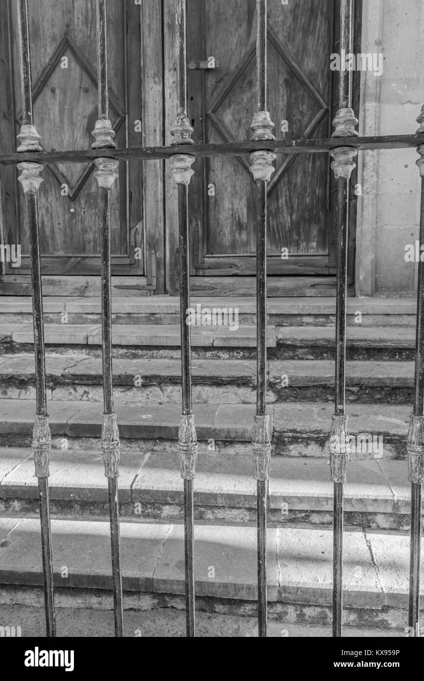 Close-up of a decorative iron gate, with stone steps and aged wooden ...