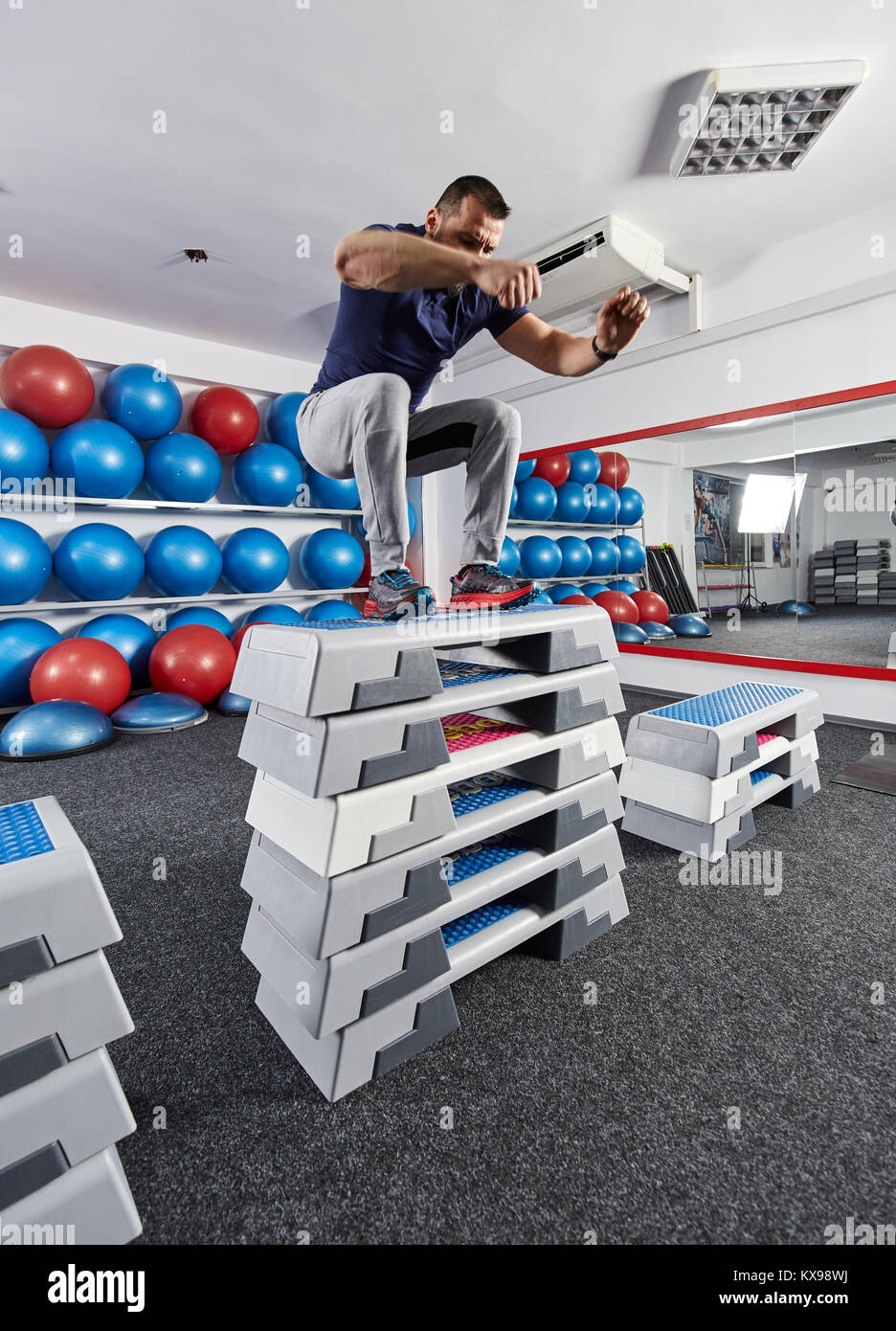Athletic man jumping on many stacked steppers Stock Photo - Alamy