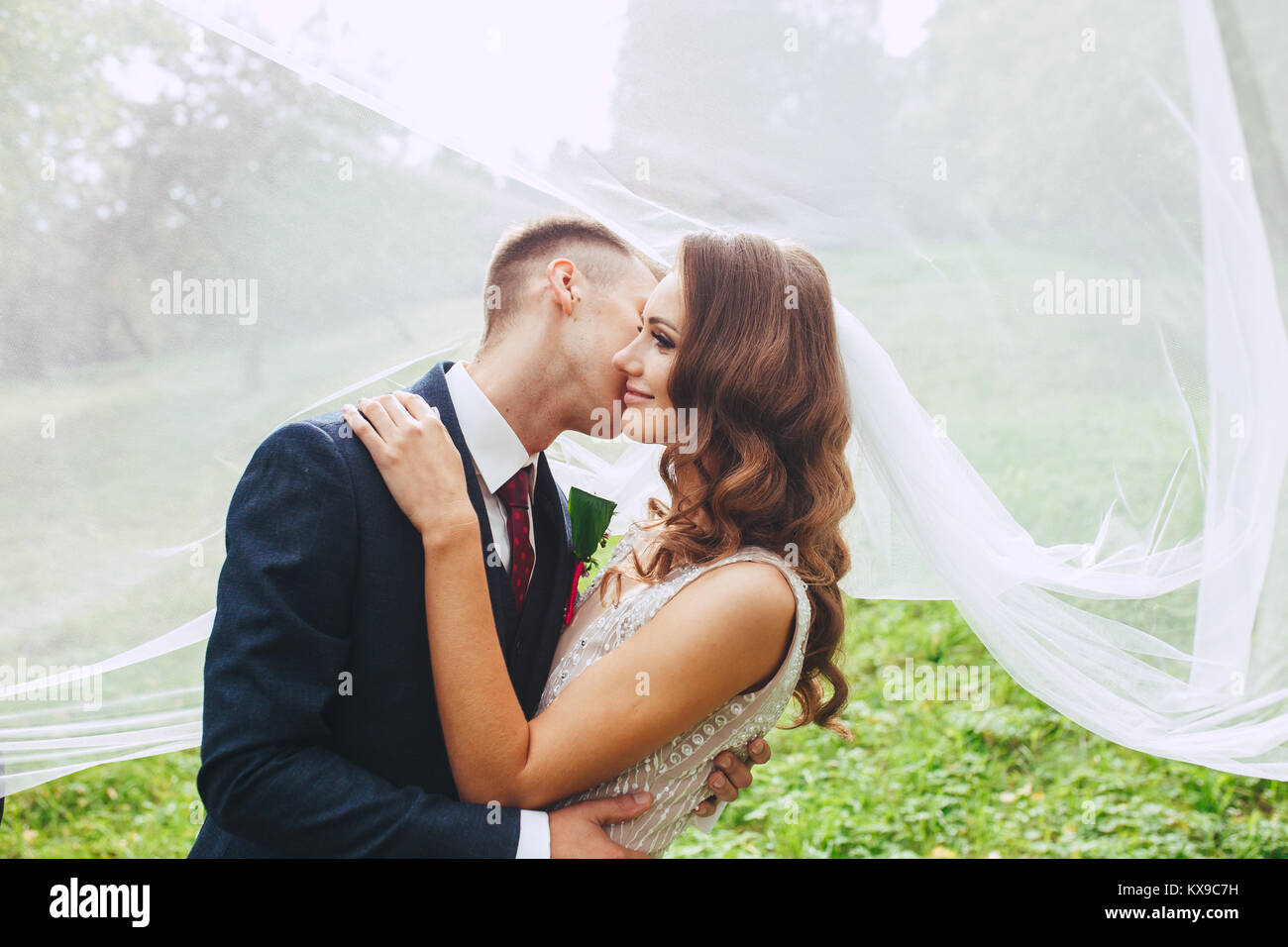close up romantic portrait of beautiful wedding couple under the veil ...