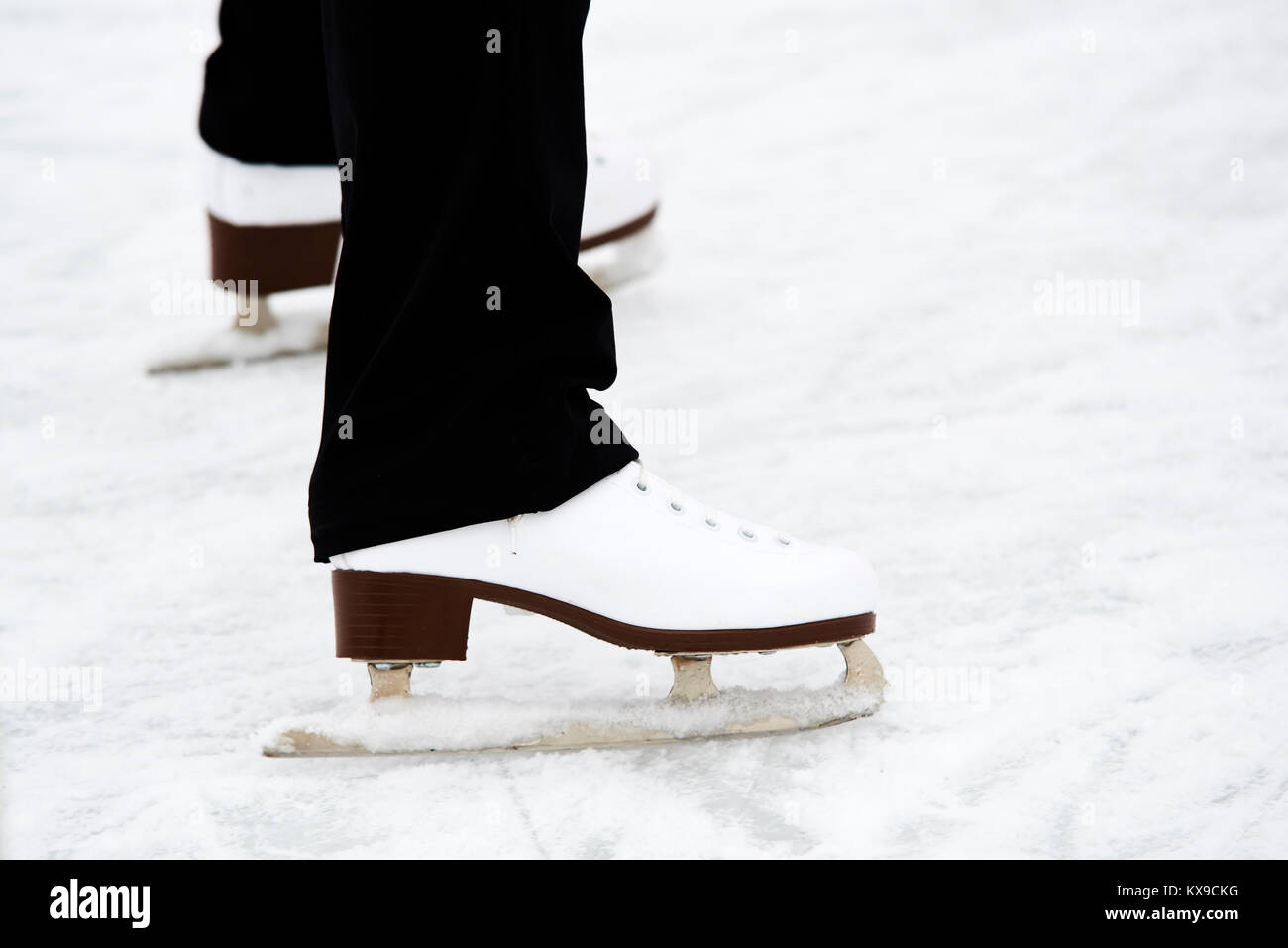 Young woman ice skating outdoors on a ice rink on a freezing winter day ...