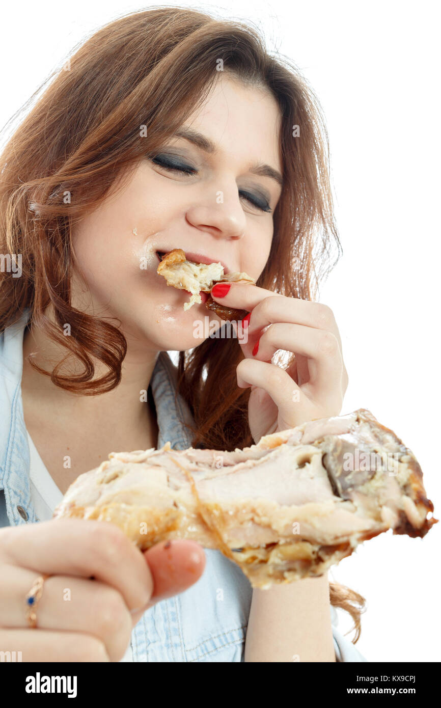 fun young woman eats fried chicken thigh on white background isolated ...