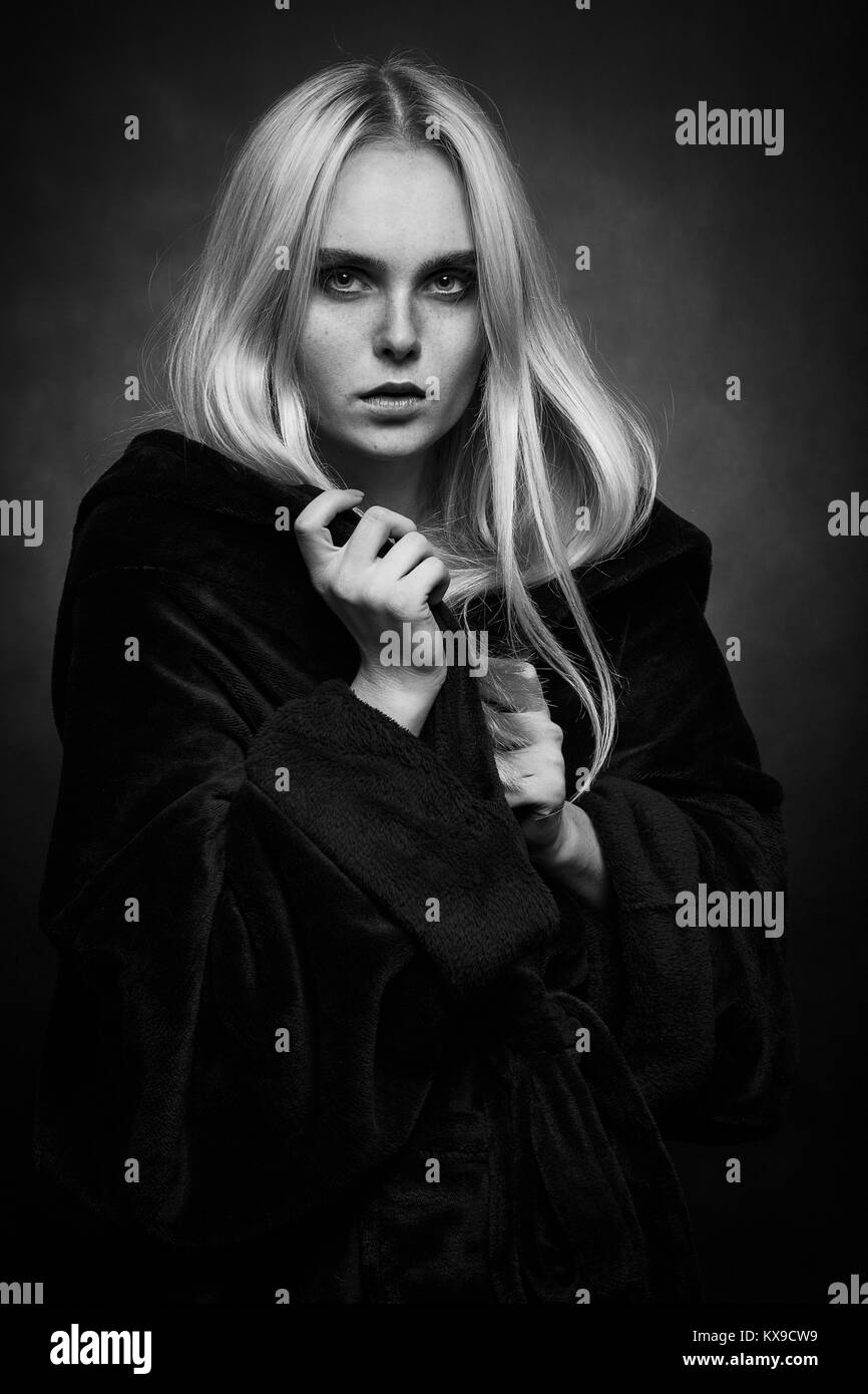 scared girl in black coat on dark background looking at camera ...