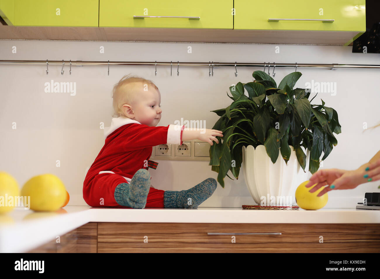 Little child in the kitchen sits on a table Stock Photo - Alamy