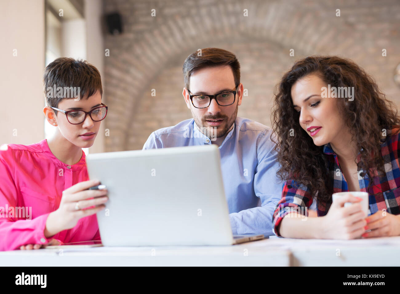 Coworkers working on project together in office Stock Photo - Alamy