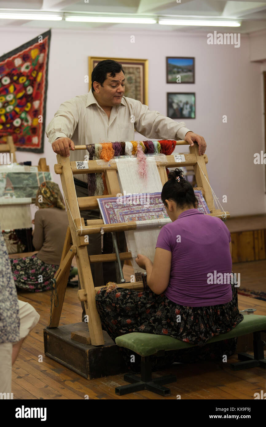 Turkish woman making wool a carpet on the cotton strings in the carpet ...
