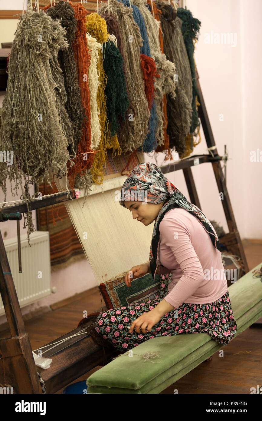 Turkish woman making wool a carpet on the cotton strings in the carpet ...