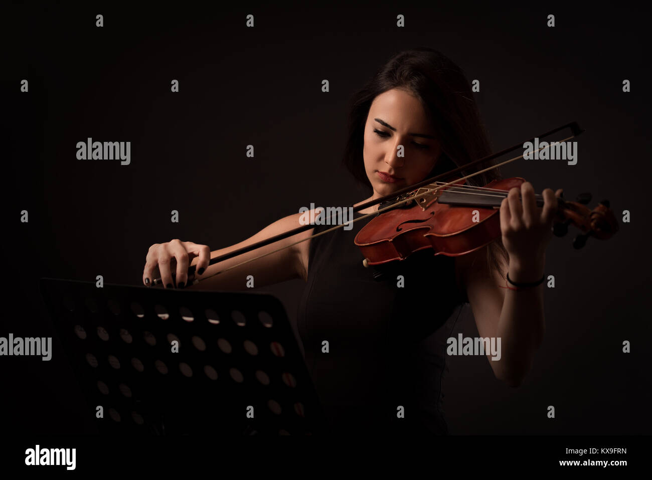 Beautiful young woman playing a violin over black background Stock ...