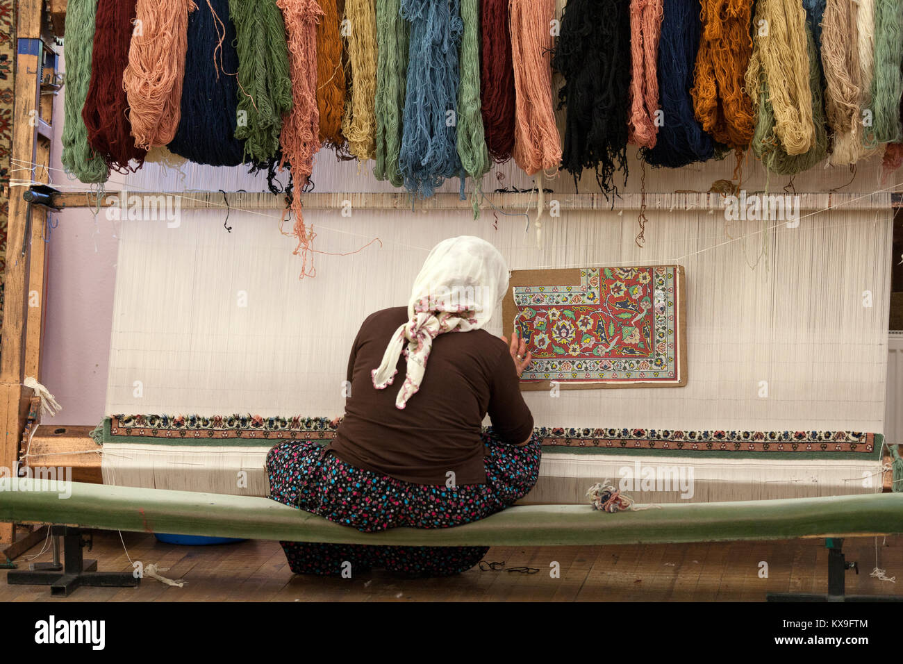 Turkish woman making wool a carpet on the cotton strings in the carpet ...