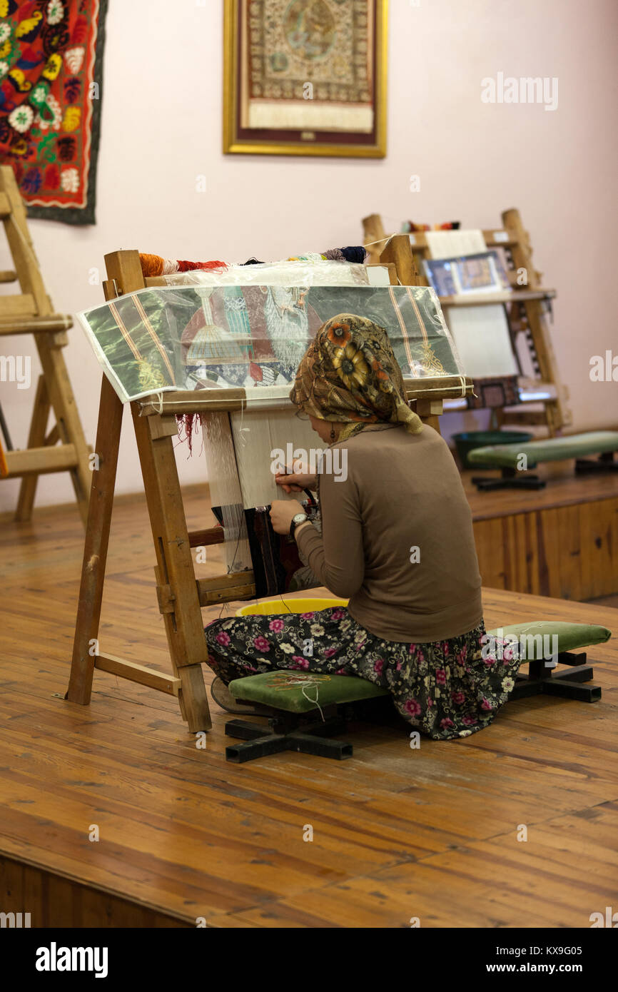 Turkish woman making wool a carpet on the cotton strings in the carpet ...