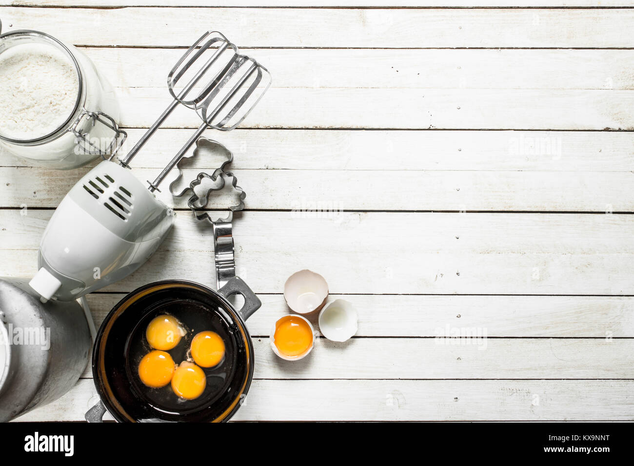 Baking background. Fresh eggs with a mixer. On a white wooden ...