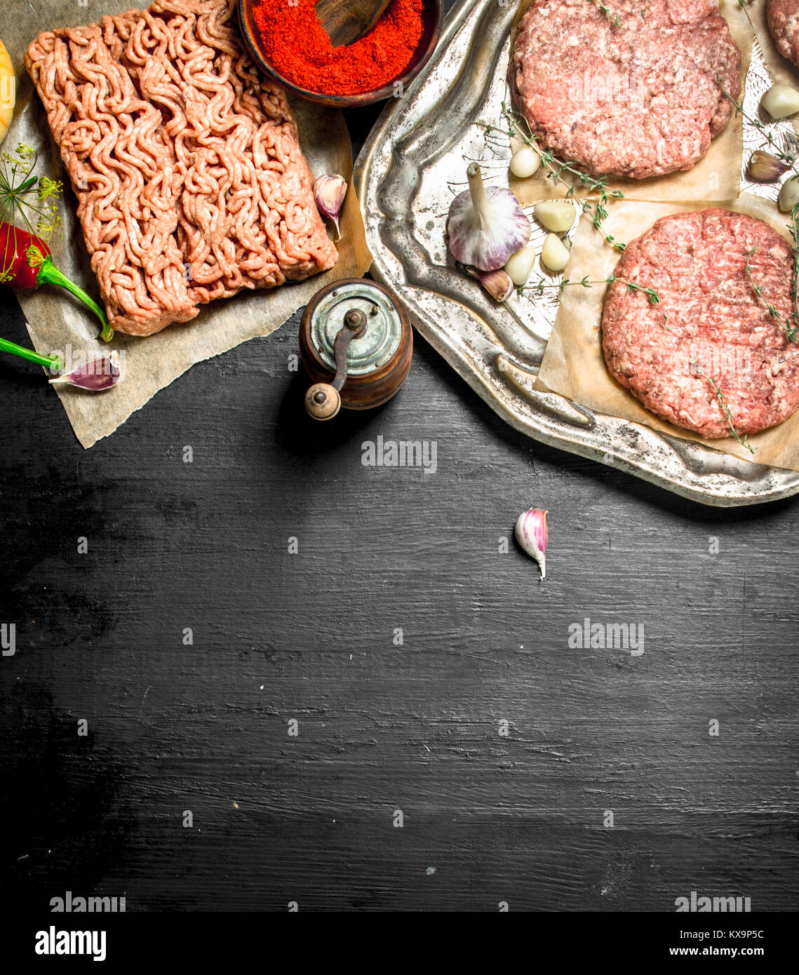 Raw burger with garlic and spices on a steel tray. On the black ...