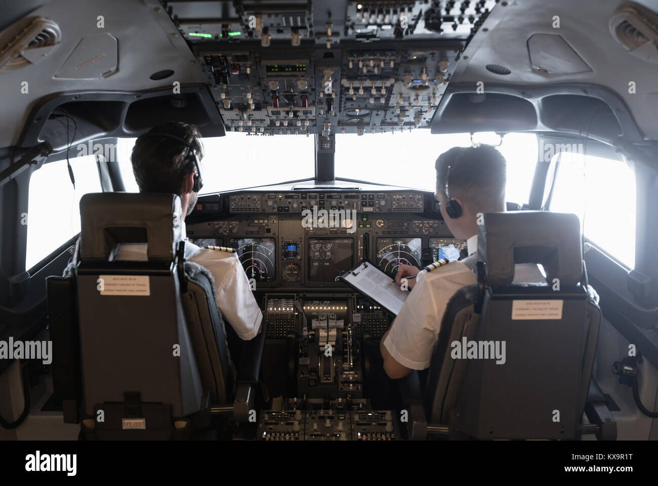 Pilot writing on clipboard while copilot flying an airplane Stock Photo ...