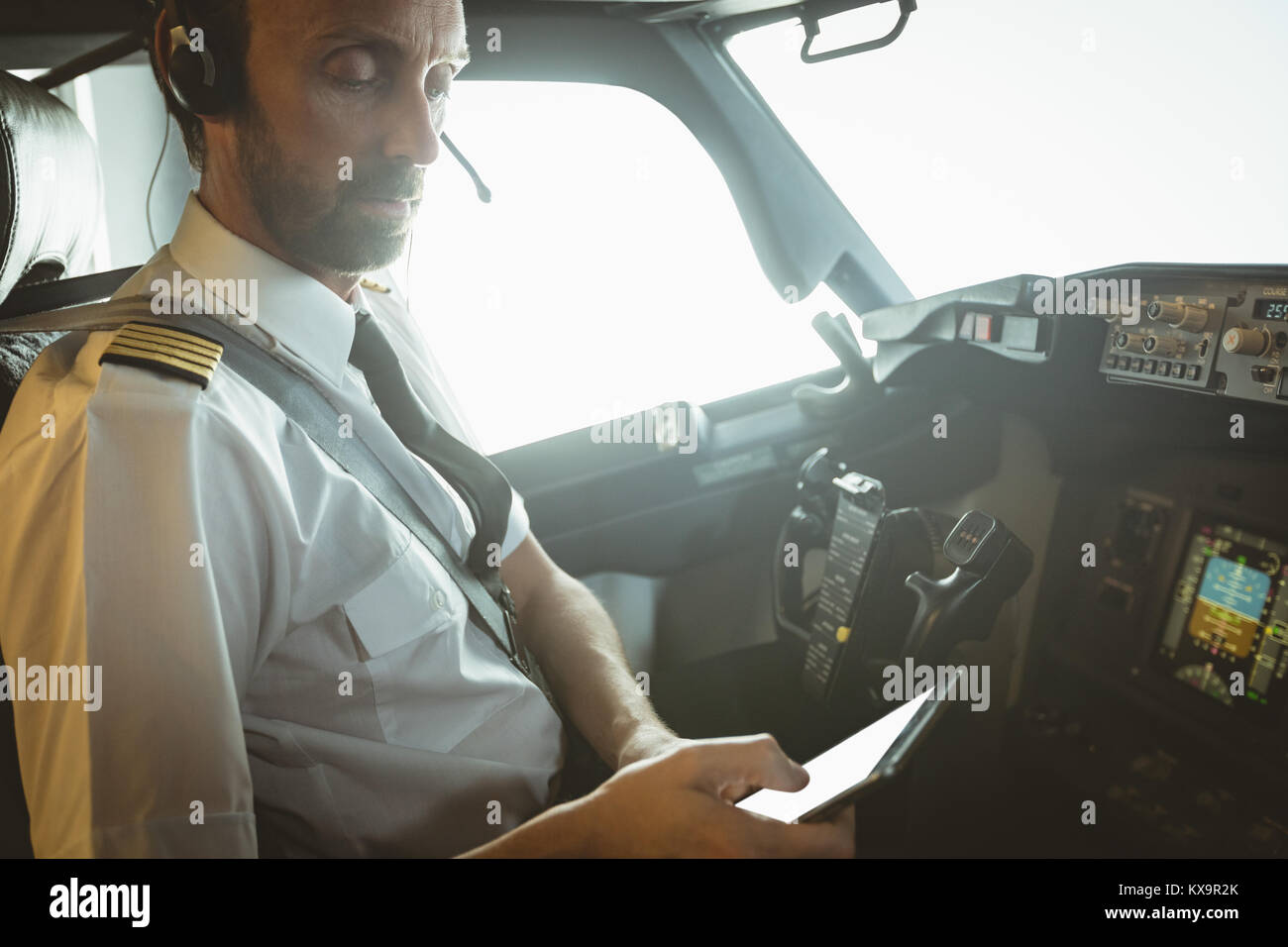 Pilot using digital tablet in airplane Stock Photo - Alamy