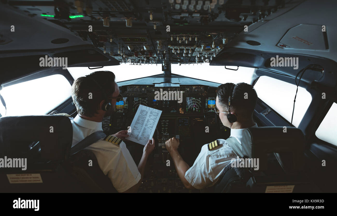 Pilot and copilot looking at instruction list in airplane Stock Photo ...