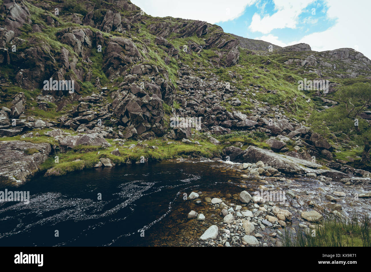 Stream flowing through the rocky green hills Stock Photo - Alamy