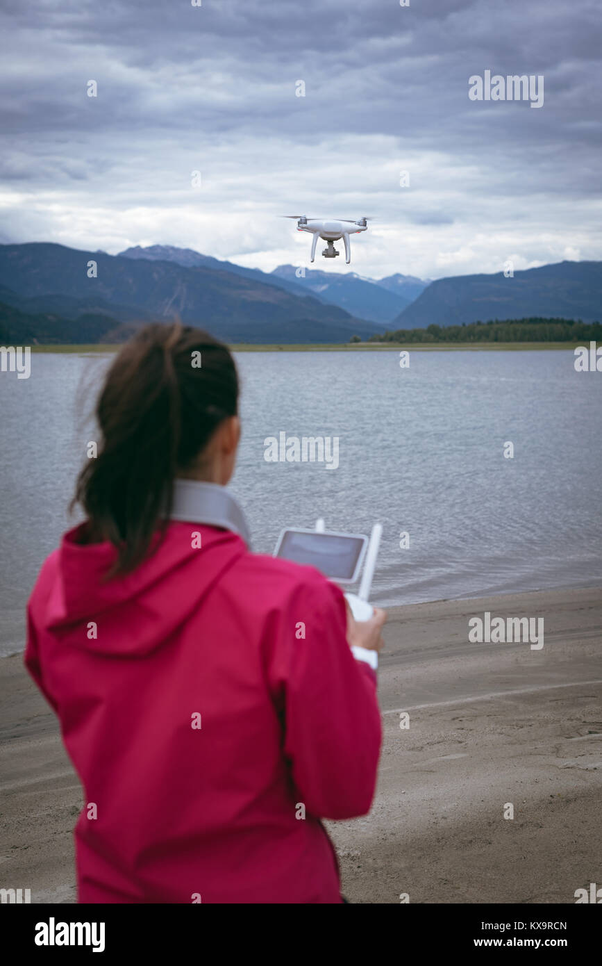 Woman operating drone flying by remote control Stock Photo - Alamy