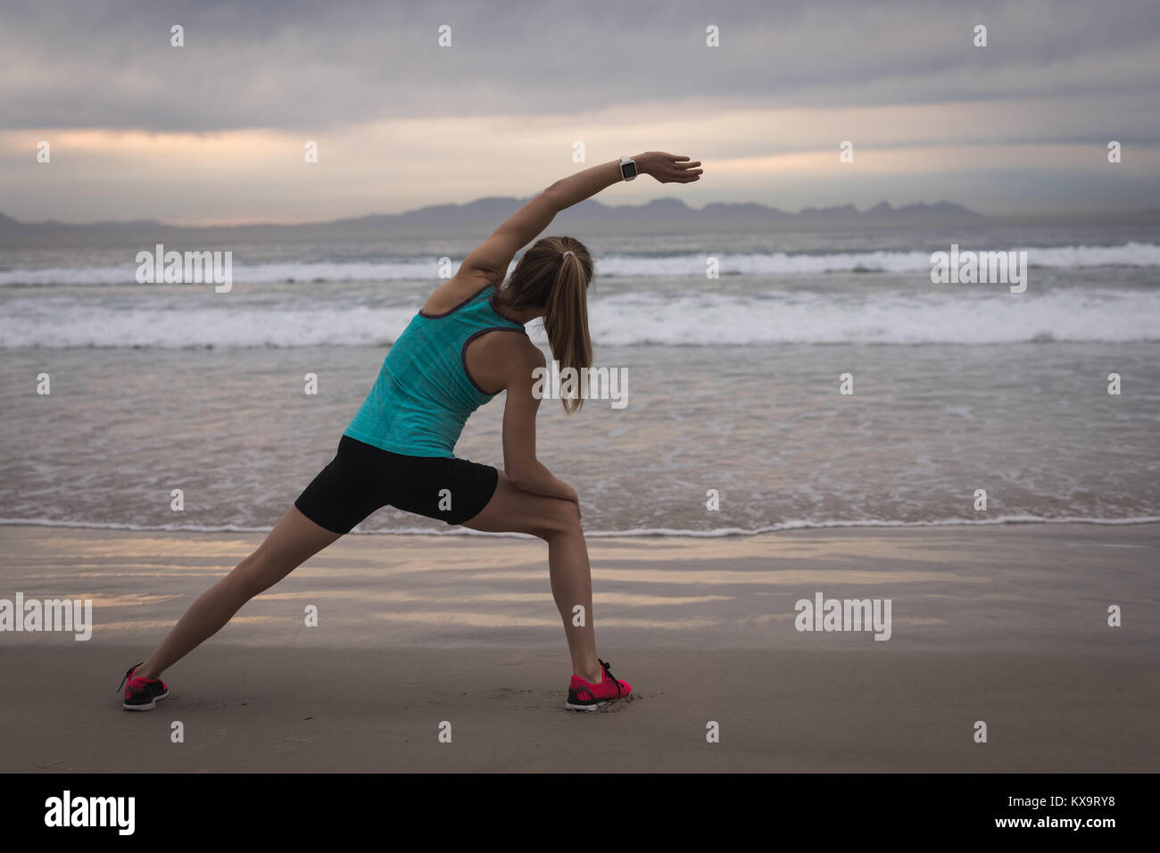 Woman performing stretching exercise on the beach during sunset Stock ...