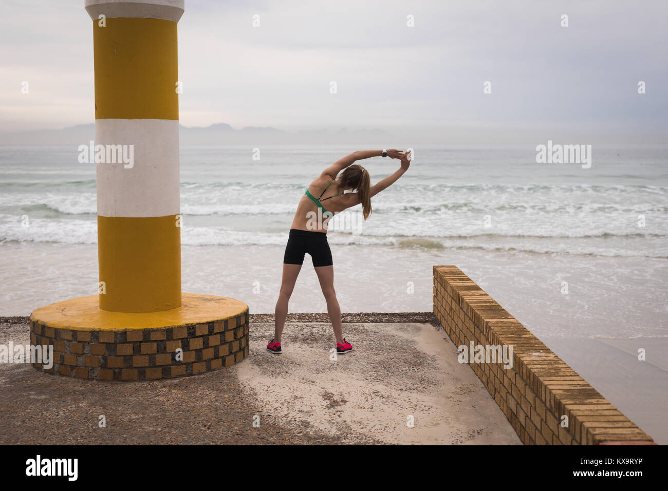 Woman performing stretching exercise near lighthouse Stock Photo - Alamy