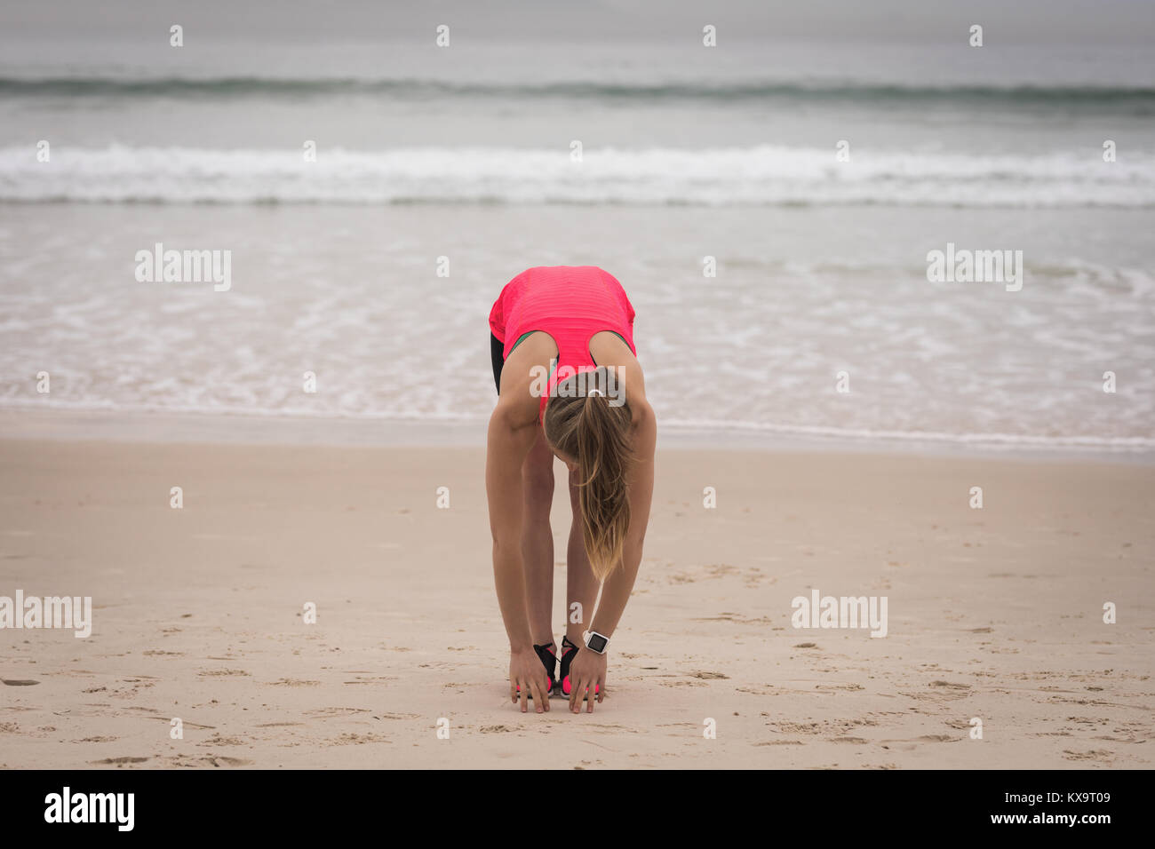 Sporty young woman bend down at the beach Stock Photo - Alamy