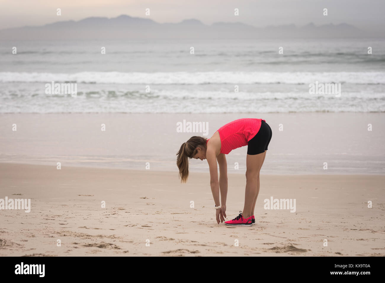 Sporty young woman bend down at the beach Stock Photo - Alamy