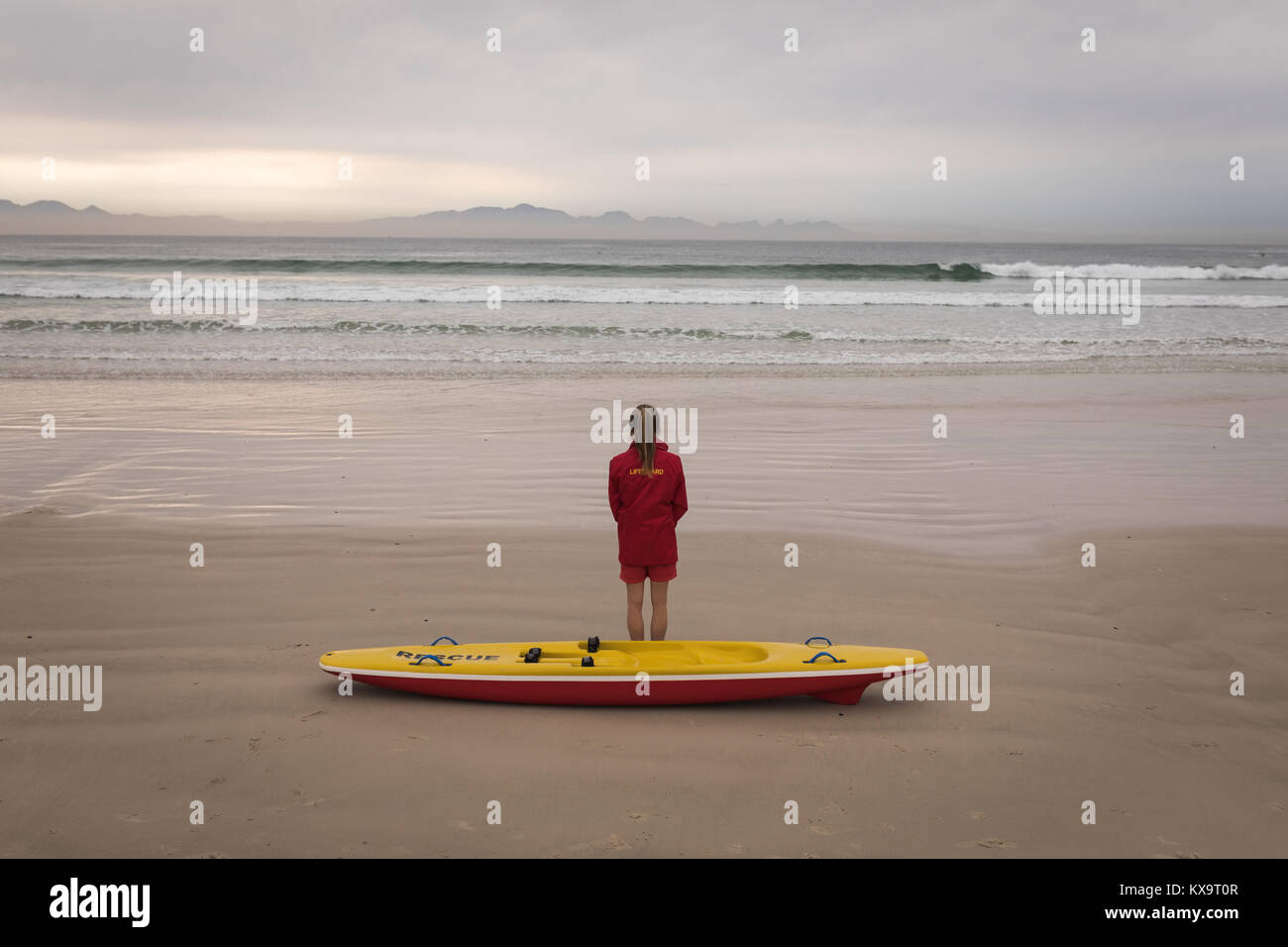 Female lifeguard standing on the beach with a rescue boat Stock Photo ...