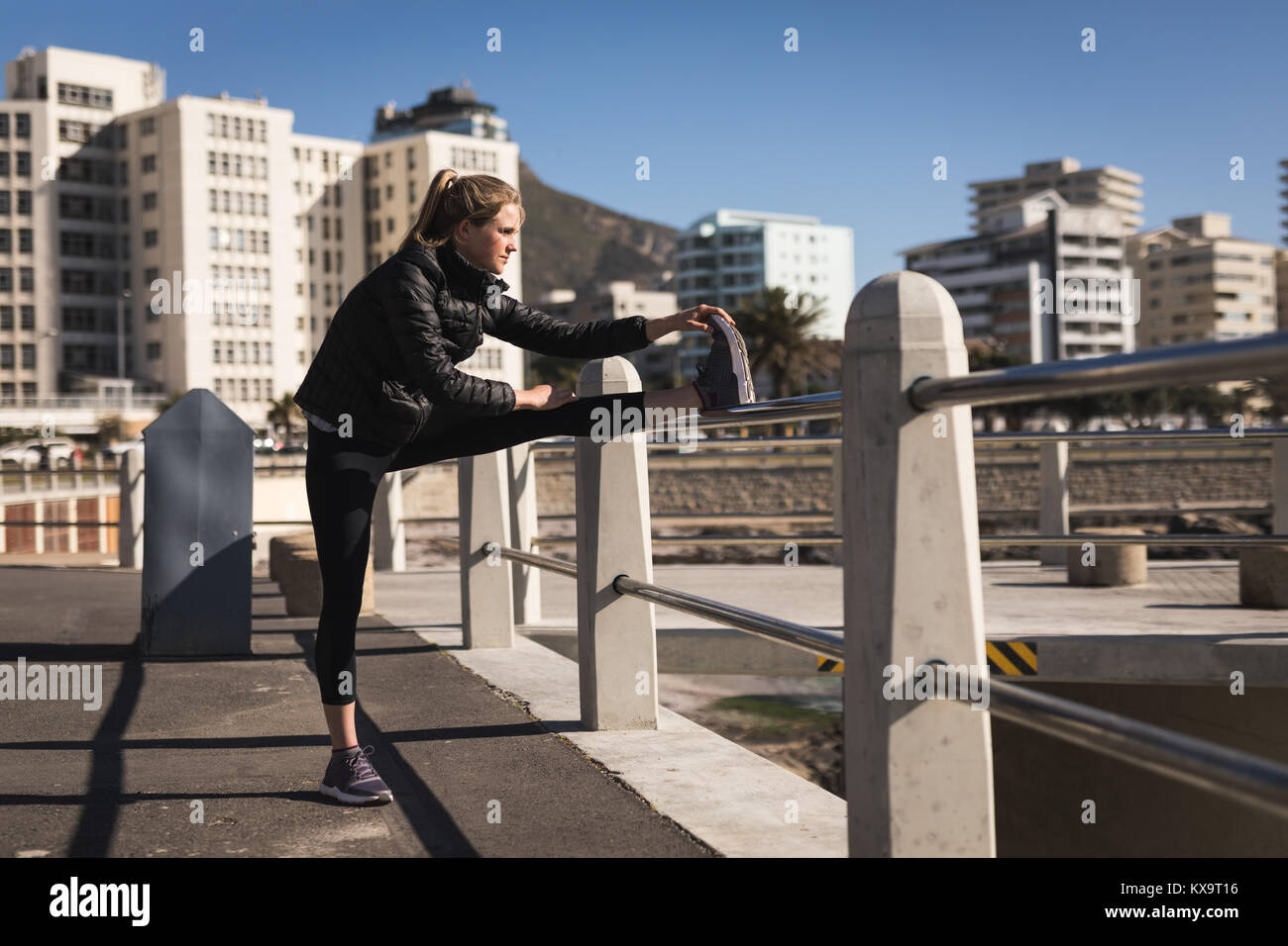 Woman performing stretching exercise on railings Stock Photo - Alamy