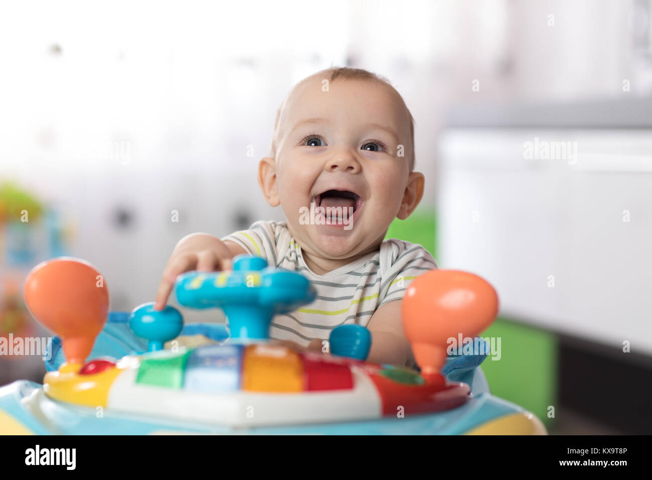 Portrait of baby toddler in baby walker. Expressive child plays toys ...