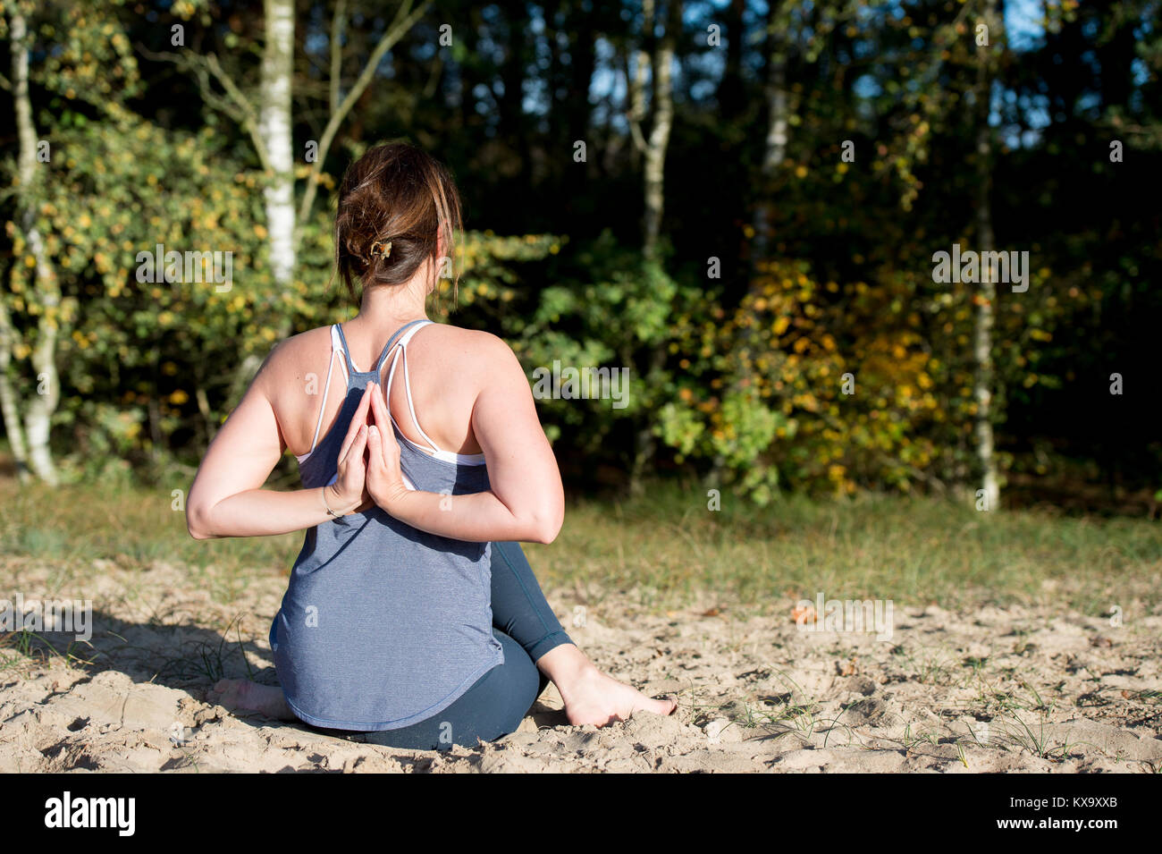 Woman practicing yoga in the sand - Cow Face Pose - Gomukhasana ...
