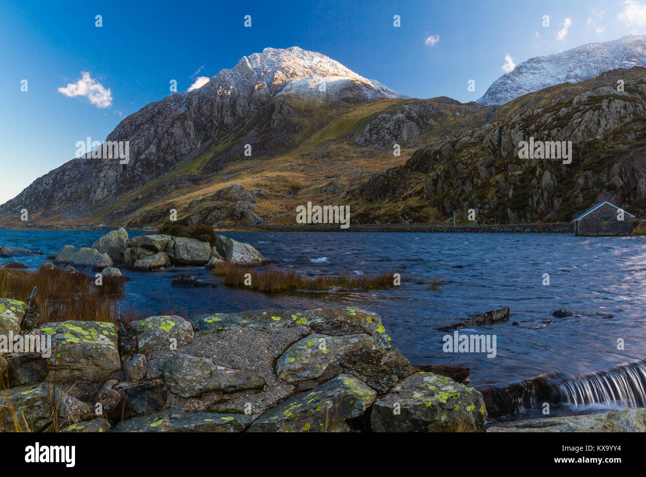 Snow capped peak of Tryfan reflected in the lake of Llyn Ogwen ...