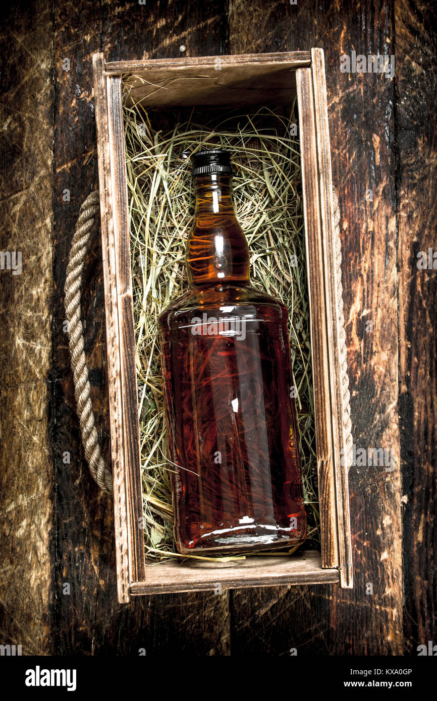 bottle of cognac in an old box. On a wooden background Stock Photo - Alamy