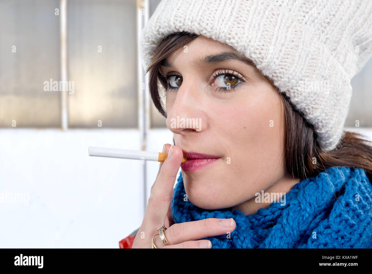 a young woman with winter cap smoking a cigarette Stock Photo - Alamy