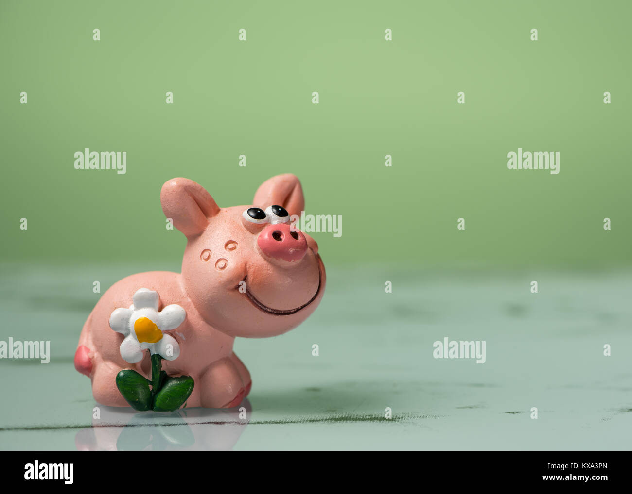 Figurine of a small piggy with a white flower, green background Stock ...