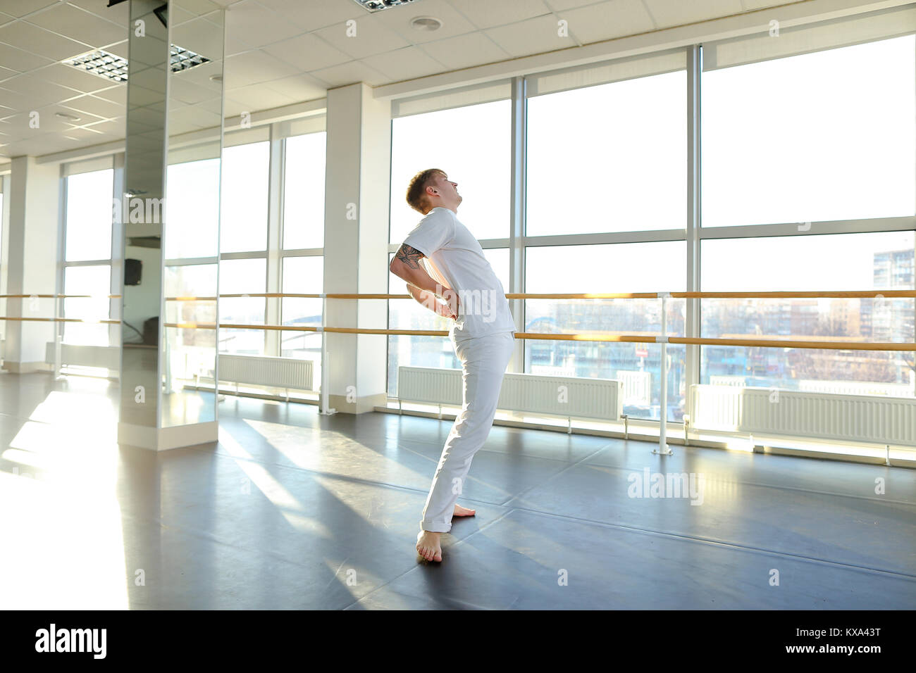 Young person making leg stretching near window Stock Photo - Alamy