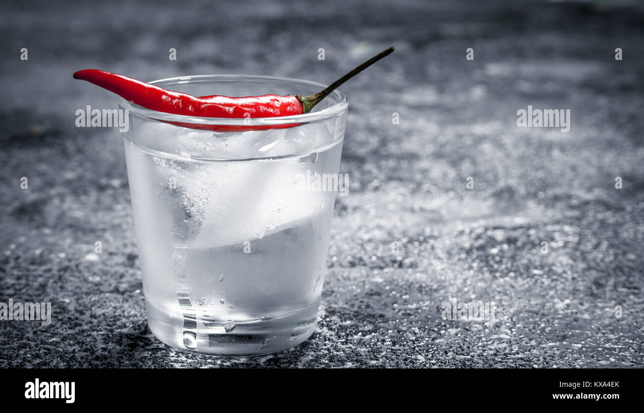 Vodka shots with hot pepper. On a rustic background Stock Photo - Alamy