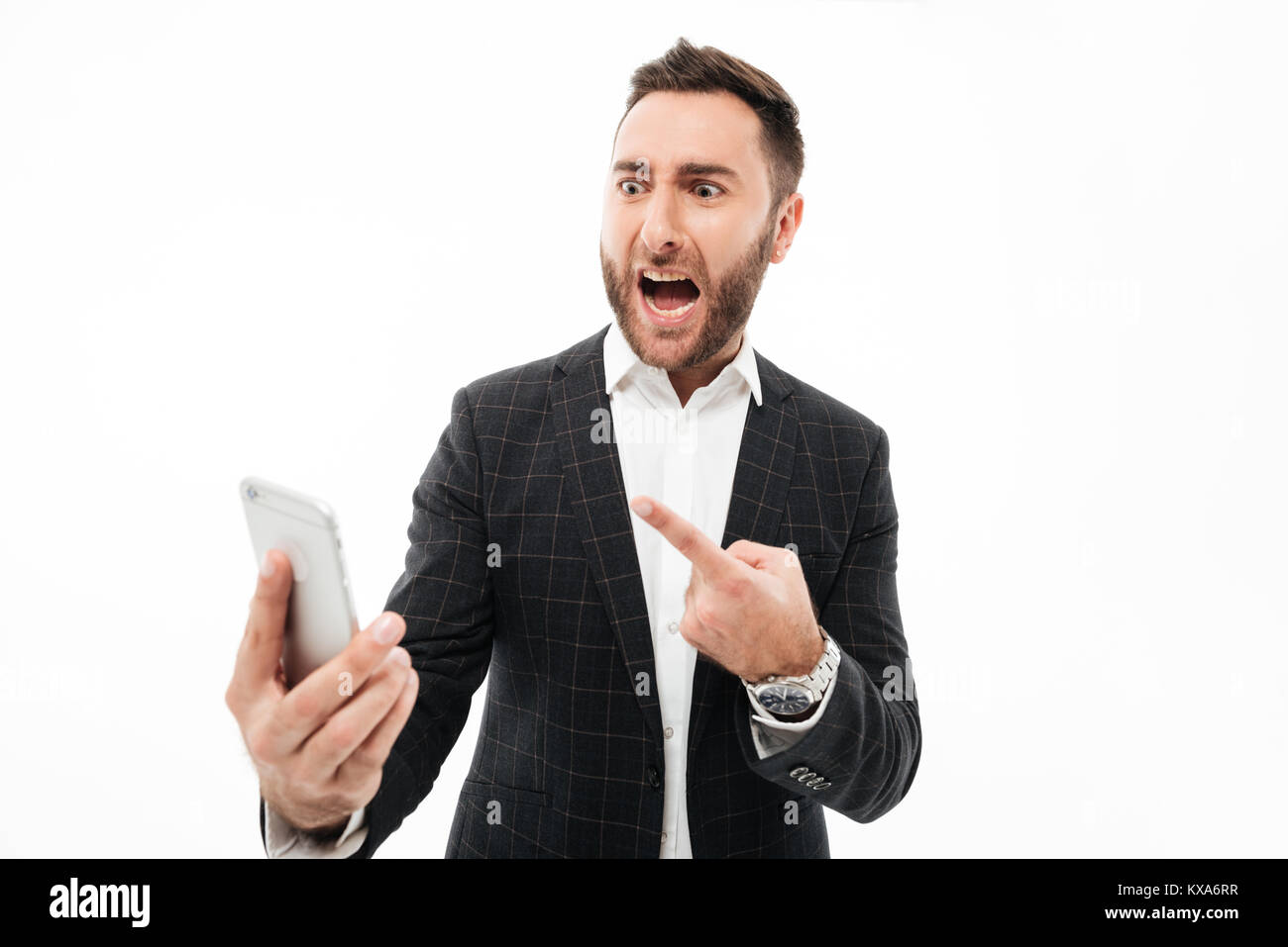 Portrait of an angry man holding mobile phone and gesturing with hands ...